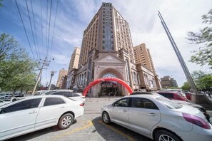Um edifício alto com uma entrada imponente e um arco vermelho.