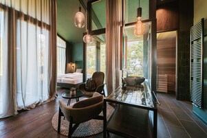 Quarto moderno com mesa de jantar de vidro, duas cadeiras, um sofá e uma cama.