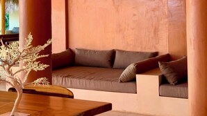 Quarto com um banco de madeira, luminária pendente e parede texturizada.