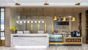 Uma área de recepção moderna com balcão de mármore, vitrine de vidro e máquina de café.