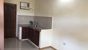 Uma cozinha compacta com pia, armários e micro-ondas.