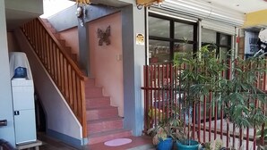 Entrada de hotel com escadas, bebedouro e plantas em vasos.