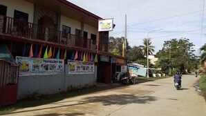 Um edifício com varanda, um letreiro com 'D&D Travellers Inn' e uma motocicleta estacionada em frente.