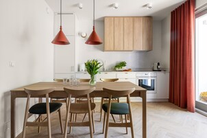 Uma cozinha moderna com armários de madeira, uma mesa de jantar com cadeiras e luminárias pendentes.