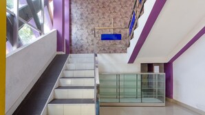 Uma escadaria com guarda-corpo de vidro, descendo para um nível inferior com divisória de vidro.