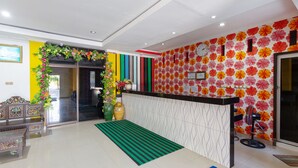 Uma área de recepção com design floral na parede, um balcão de atendimento e um espaço de estar com um tapete estampado.