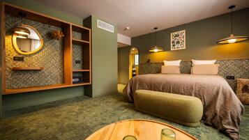 Quarto com cama grande, um banquinho de madeira, um espelho e uma prateleira com artigos de higiene pessoal.