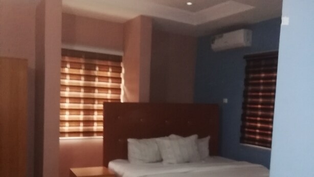 Um quarto com cama, mesas de cabeceira, um banco de madeira e um guarda-roupa.