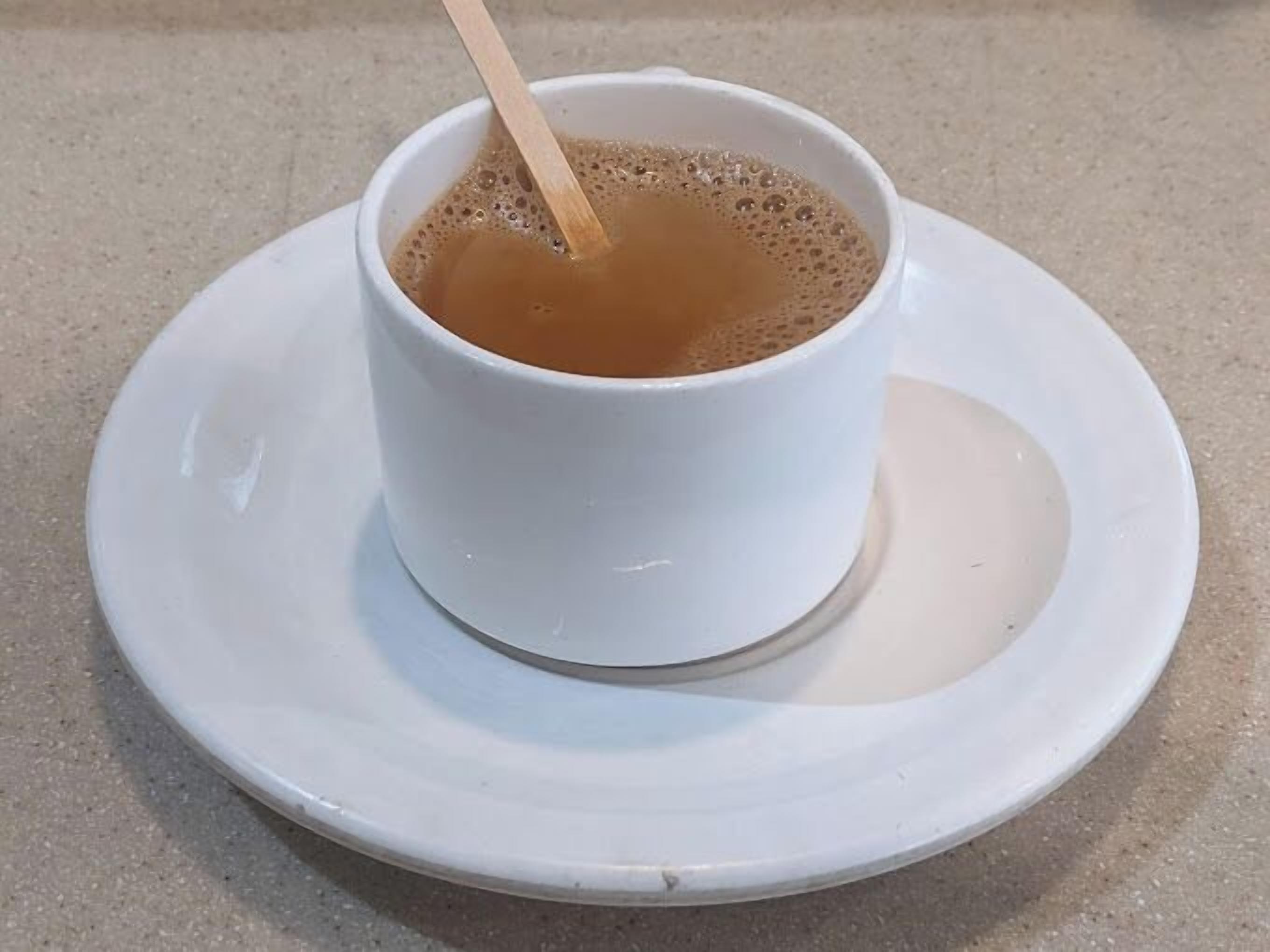 Uma chávena de café branco sobre um pires.