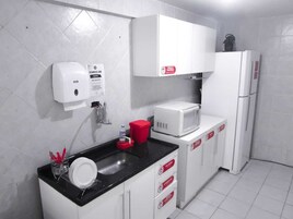 Cozinha moderna com armários brancos, bancada preta, micro-ondas e geladeira.