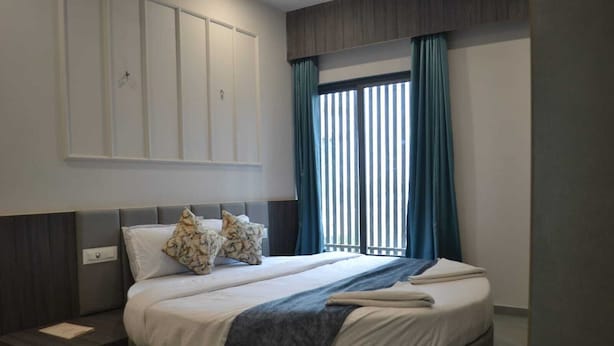 Quarto moderno com cama redonda, mesa de cabeceira, guarda-roupa e janela com cortinas.