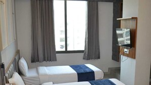 Quarto de hotel com duas camas, uma televisão e um ar condicionado.