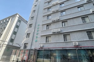 Um edifício de vários andares com arquitetura moderna, apresentando uma série de janelas e aparelhos de ar condicionado na fachada.