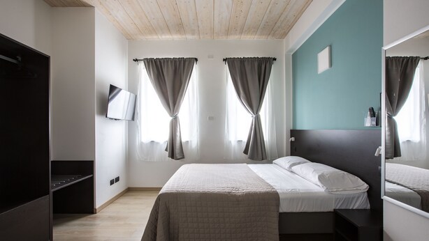 Quarto moderno com cama, televisão e guarda-roupa.