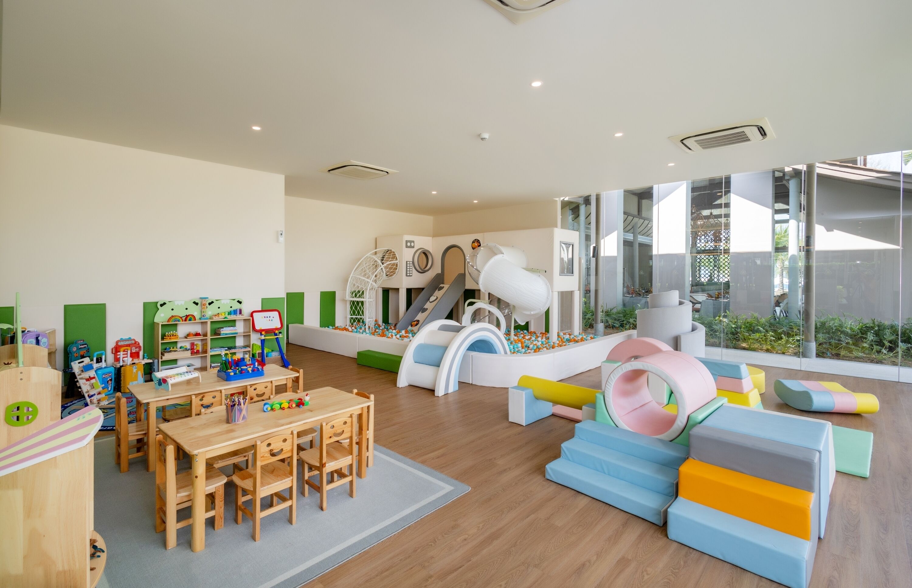 Uma área de recreação infantil com escorregador, estruturas de escalada e tapetes de atividades coloridos.