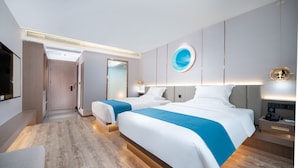 Quarto de hotel moderno com duas camas, um espelho grande, uma televisão de tela plana e uma mesa de cabeceira com abajur.