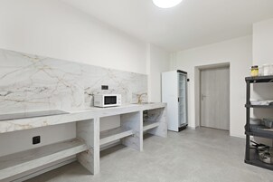 Uma cozinha moderna com painel de backsplash de mármore, micro-ondas embutido e eletrodomésticos de aço inoxidável.