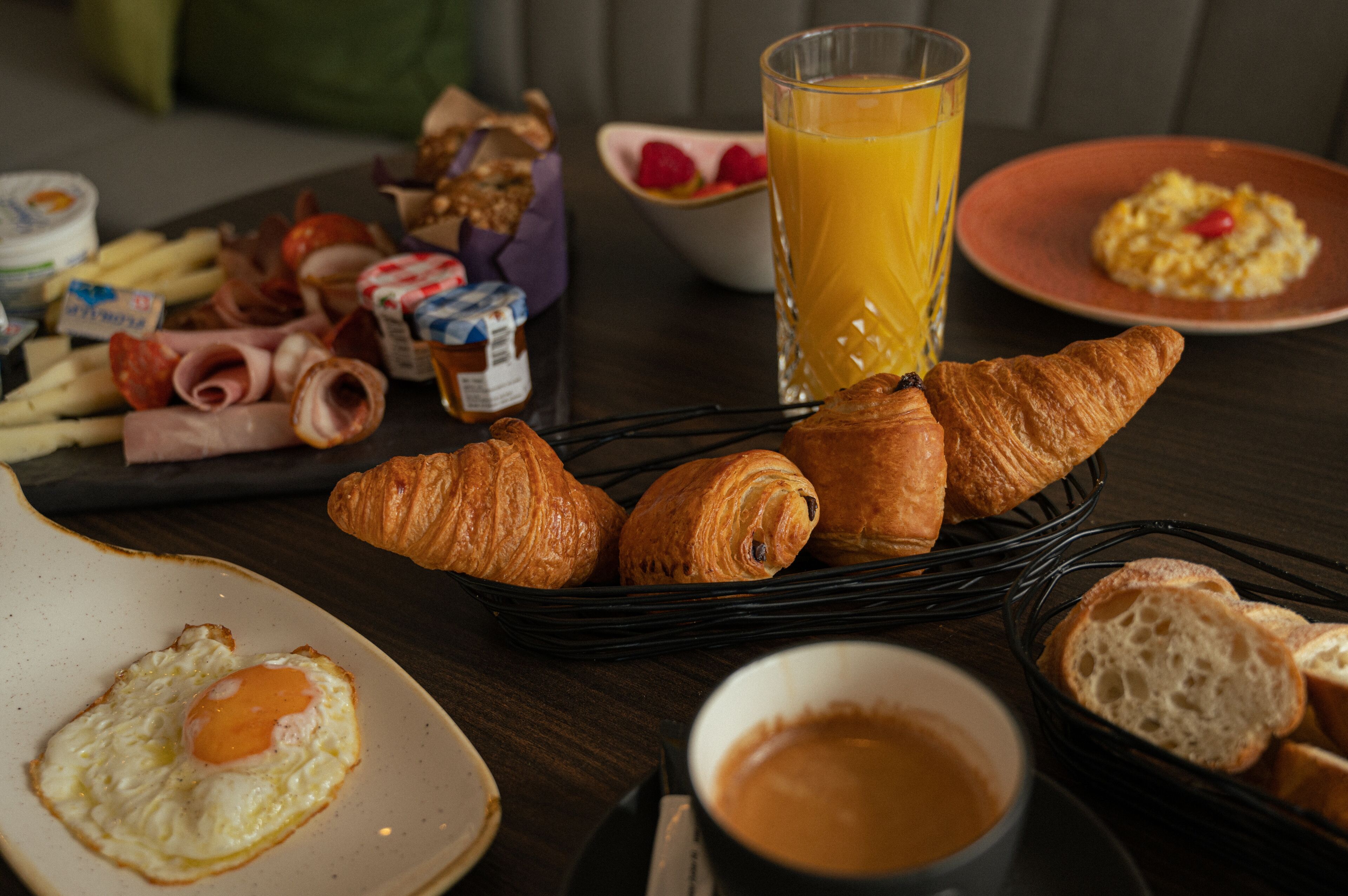 Uma mesa com croissants, ovos e um copo de sumo de laranja para o pequeno-almoço.