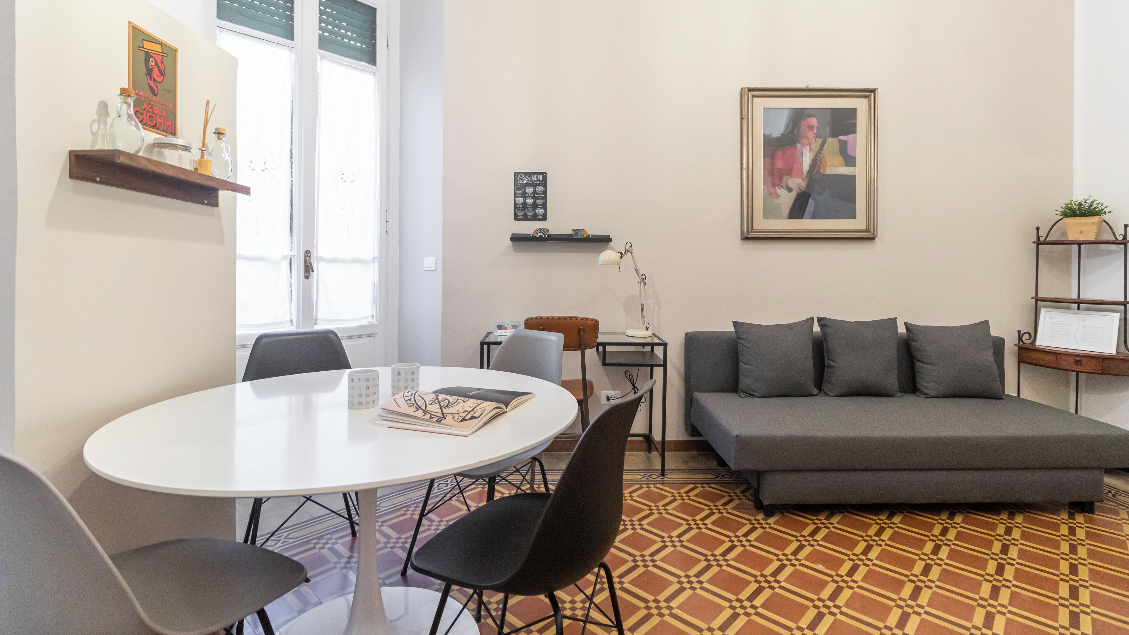 Uma sala de estar moderna com uma mesa redonda branca, sofá cinza e piso estampado.