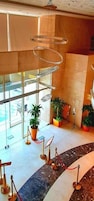 Um hall com um lustre moderno, plantas em vasos e uma entrada de vidro para uma área externa.