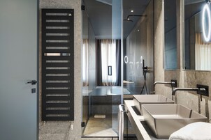 Uma casa de banho moderna com chuveiro em cabine de vidro, um espelho grande e lavatório embutido.