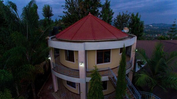 Um edifício com várias andares e telhado vermelho, cercado por vegetação exuberante.