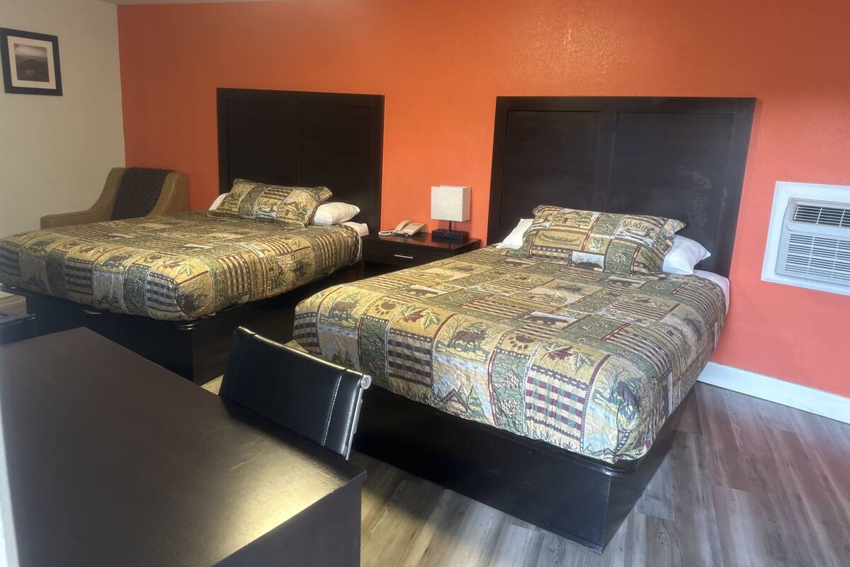Quarto de hotel com duas camas, uma mesa e uma cadeira.