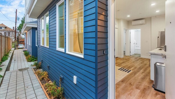 Uma casa moderna com fachada azul, área de cozinha visível e um caminho que leva à entrada.