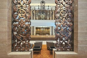 Um hall com divisórias de madeira elaboradas, um lustre e área de estar.