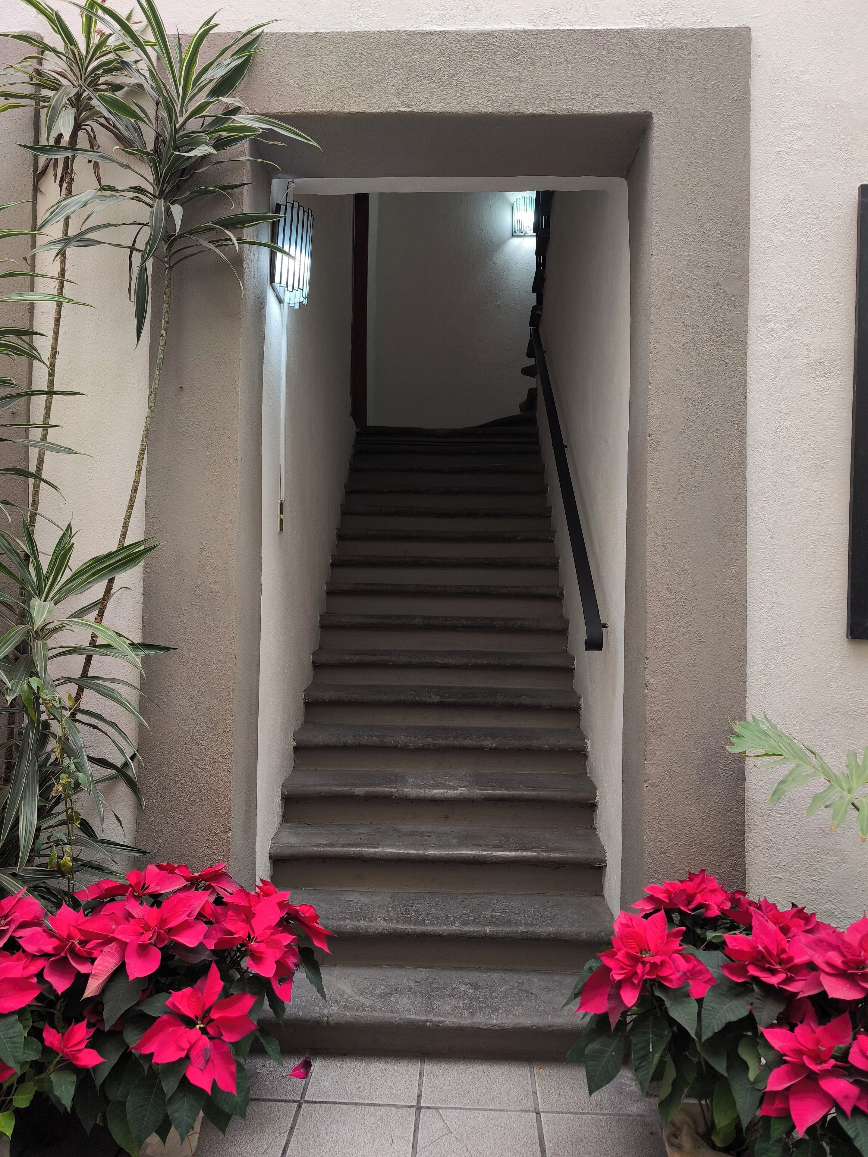 Escadaria que leva a um patamar com luminária suspensa.