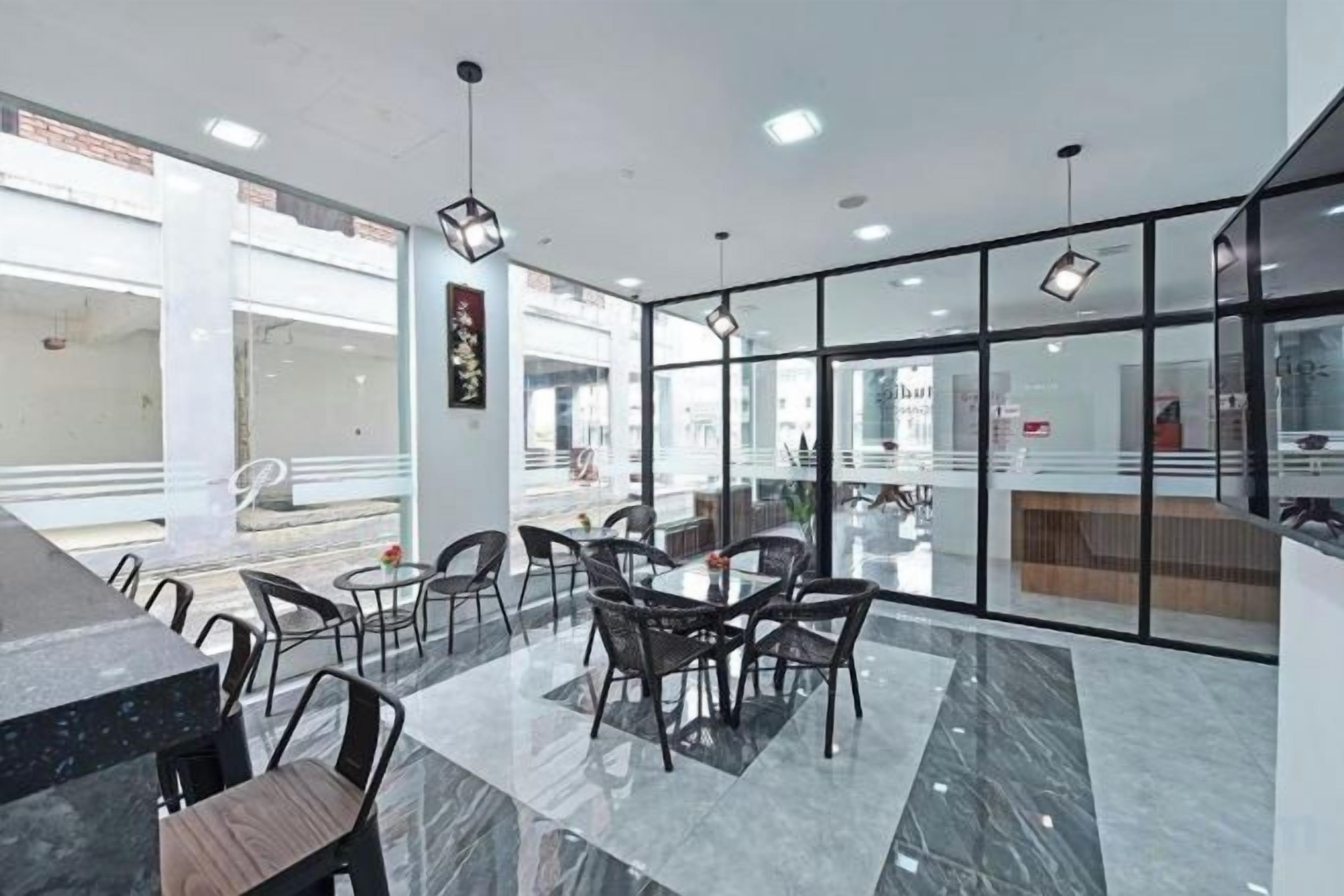 Um hall de hotel moderno com piso de mármore, divisórias de vidro e mobiliário contemporâneo.