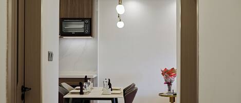 Cozinha moderna com micro-ondas embutido, área de jantar com mesa e cadeiras, e uma pequena mesinha lateral com um vaso.