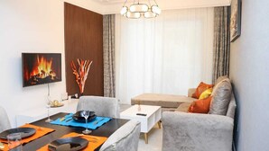 Uma sala de estar moderna com área de jantar, um conjunto de sofá, uma TV de tela plana e um vaso decorativo.