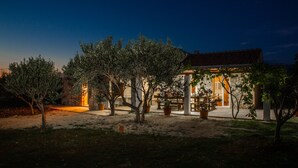 Uma vila rústica com fachada de pedra, área de estar ao ar livre e um jardim bem cuidado ao entardecer.