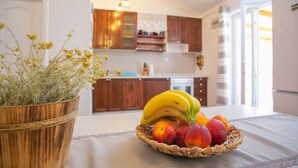 Uma cozinha com armários de madeira, uma cesta de frutas sobre a mesa e uma planta em vaso.