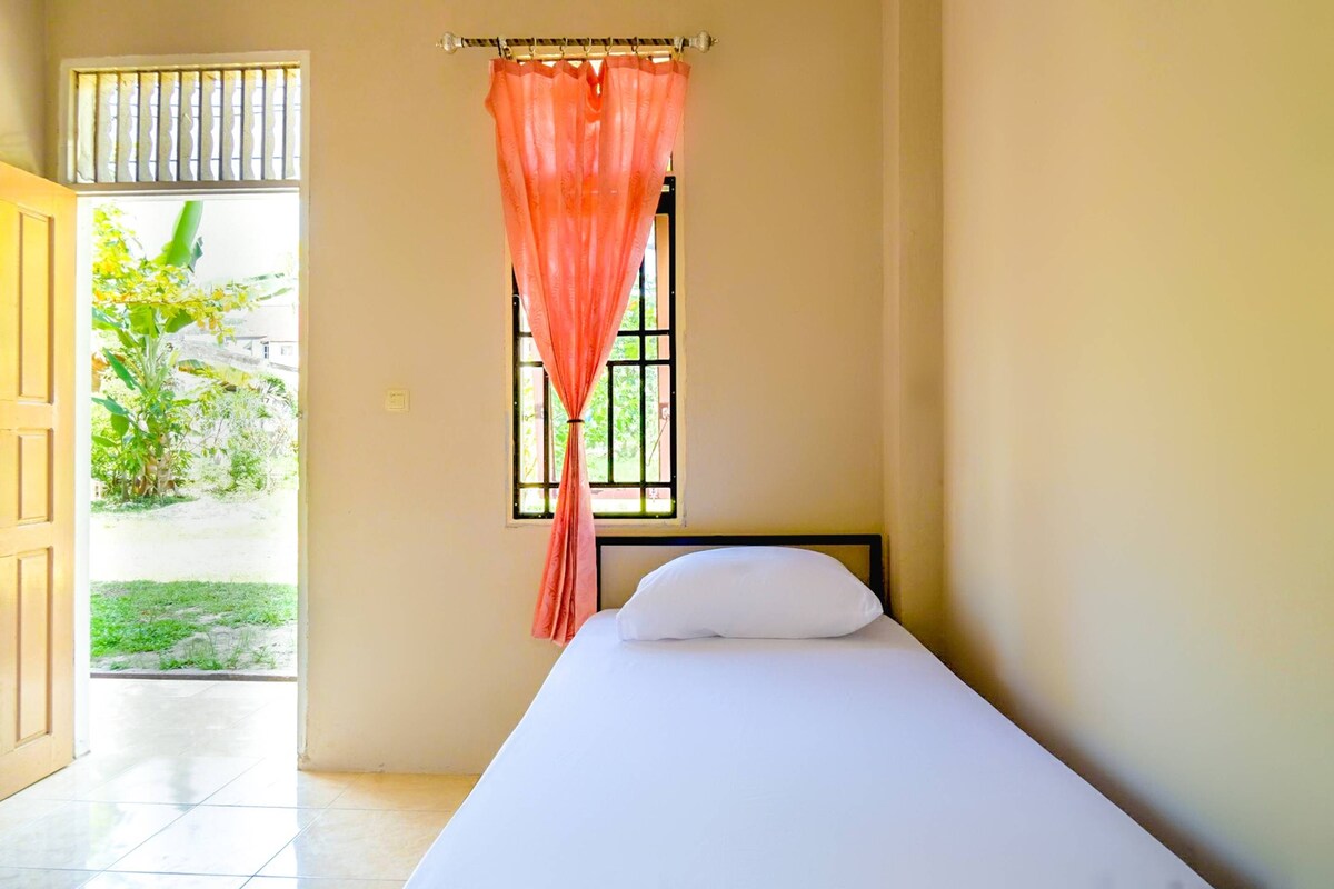 Quarto com uma cama, janela com vista para vegeta ção e porta que dá para o exterior.