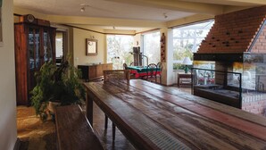 Uma sala de estar ampla com um banco de madeira, uma mesa de jantar e uma lareira de tijolos.