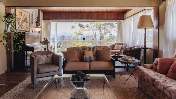 Uma sala de estar aconchegante com sofá, poltronas, mesa de centro e piano.