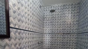 Casa de banho com padrão de mosaico em espinha de peixe, sanita e zona de duche.