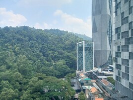 Um edifício moderno com fachada de vidro e vista para uma encosta verde exuberante.