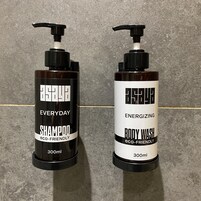Duas garrafas de shampoo e líquido de banho com dosadores, ambas com a etiqueta eco-friendly e 300ml cada.