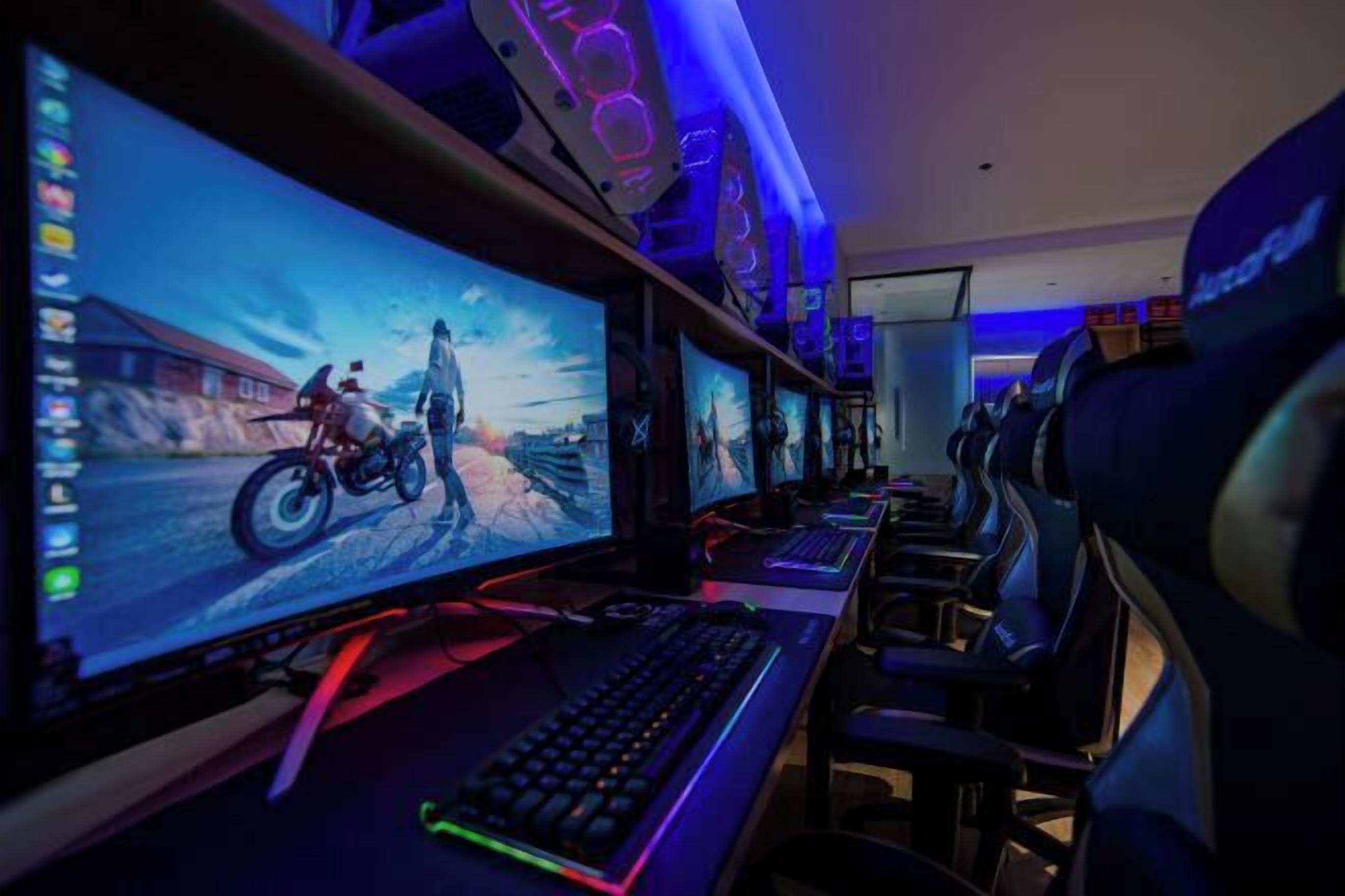 Vários computadores para jogos dispostos em linha, cada um exibindo cenas de jogos.