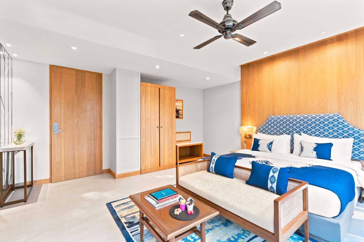 Um quarto com cama, mesa de cabeceira, ventilador de teto e guarda-roupa.