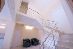 Um interior espaçoso com uma escadaria moderna, duas poltronas de couro preto e uma porta.