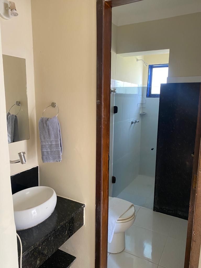 Casa de banho com uma pia branca, um espelho e um porta-toalhas.