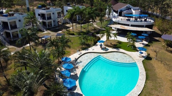 Um resort com uma grande piscina, vários edifícios para hóspedes e palmeiras.