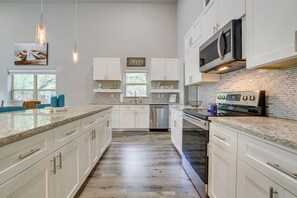 Uma cozinha moderna com armários brancos, eletrodomésticos de aço inoxidável e bancada de granito.