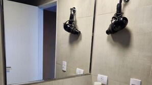 Um banheiro moderno com um espelho grande, uma pia branca e dois dispensadores de toalhas pretos.