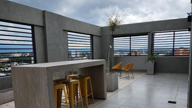 Terraço no telhado com área de bar, assentos e janelas amplas com vista para a cidade.