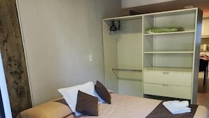 Quarto de hotel com cama, guarda-roupa e banheiro à mostra.